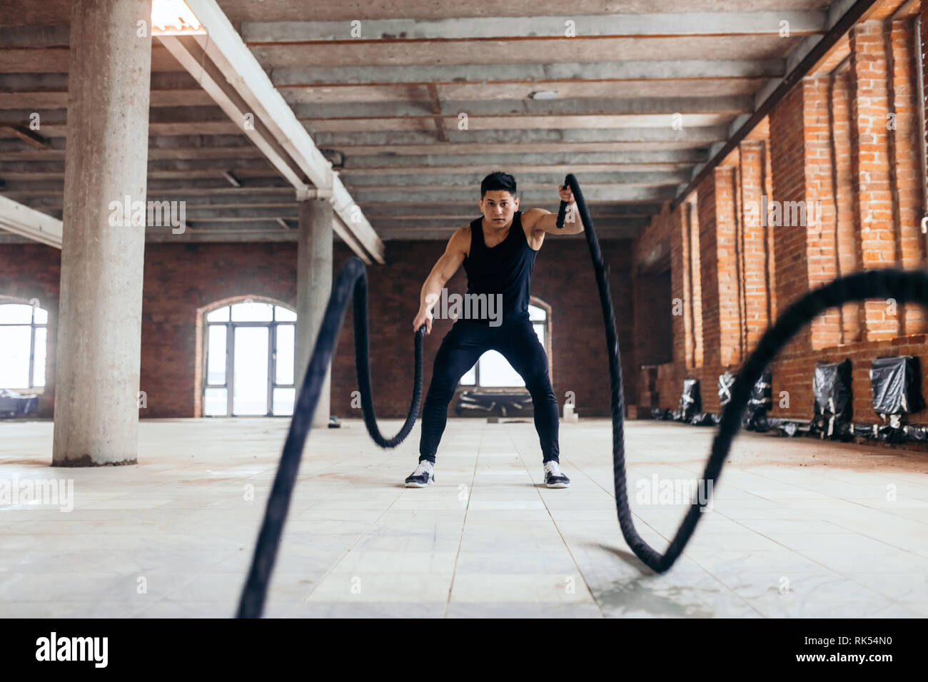 gorgeous man taking an end of the rope and raising one arm to shoulder ...
