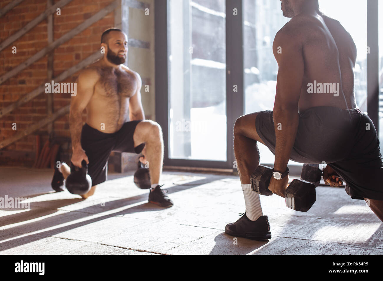 Powerful crossfit mixed race athletes in a deep lunge with a heavy ...