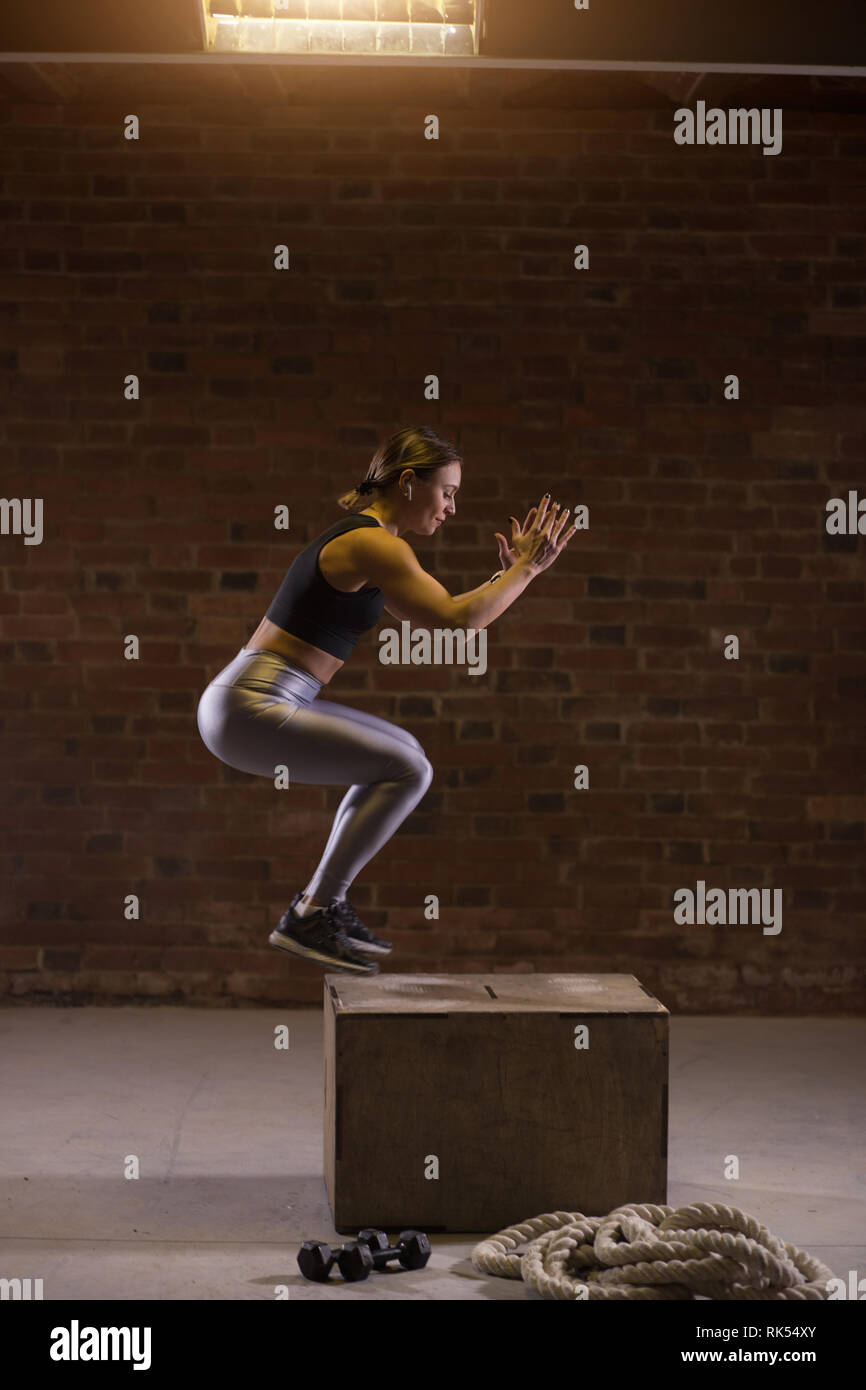 Young fit caucasian woman doing a box jump exercise. Muscular woman ...