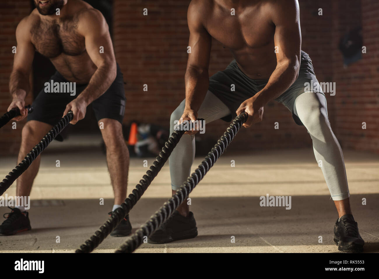 Two multiethnic shirtless male bodybuilders are exercising with ...