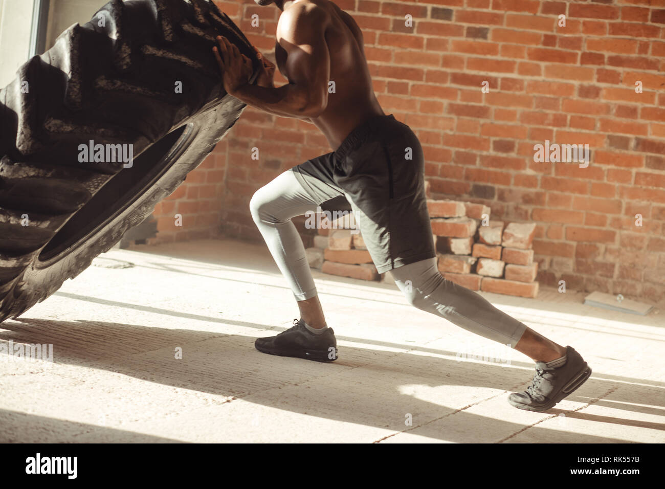 African american crossfit man makes an effort while pushing hard with ...