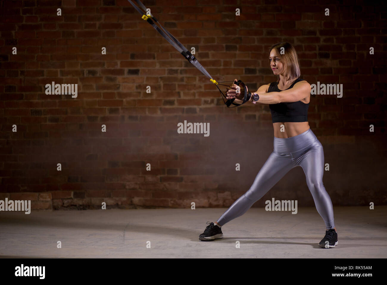 Crossfit female instructor doing full body TRX session workout in gym ...