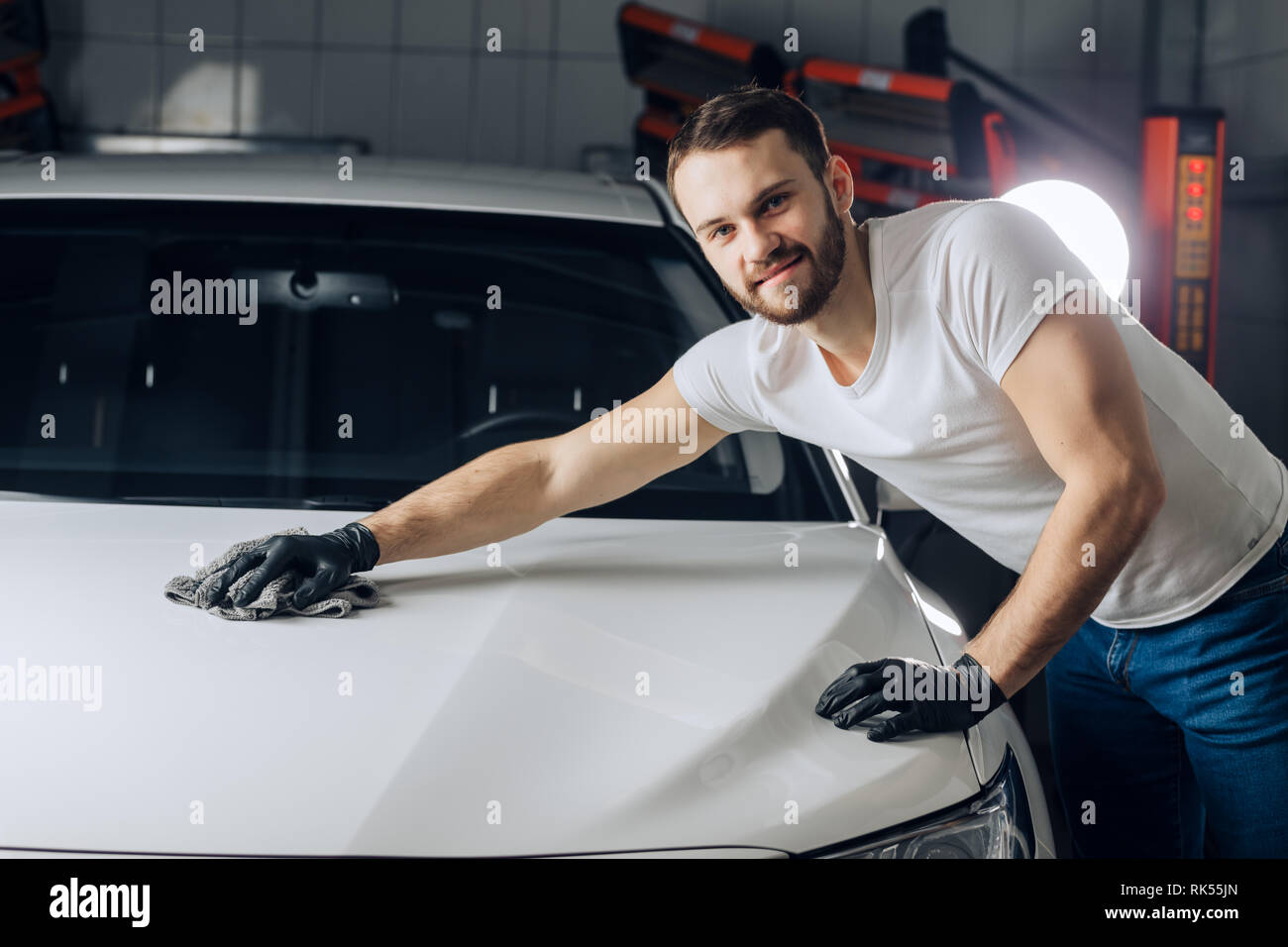 positive good looking mechanic cleaning the surface of his car at the ...
