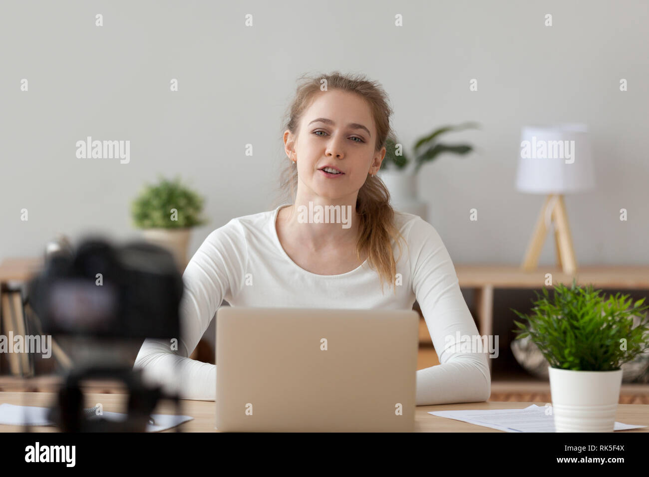 Friendly millennial girl youtuber talking to camera shooting ...