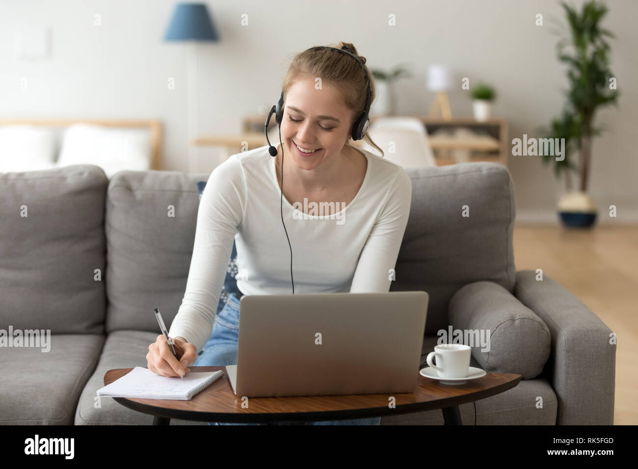 Happy girl interpreter in headset write notes study on laptop Stock ...