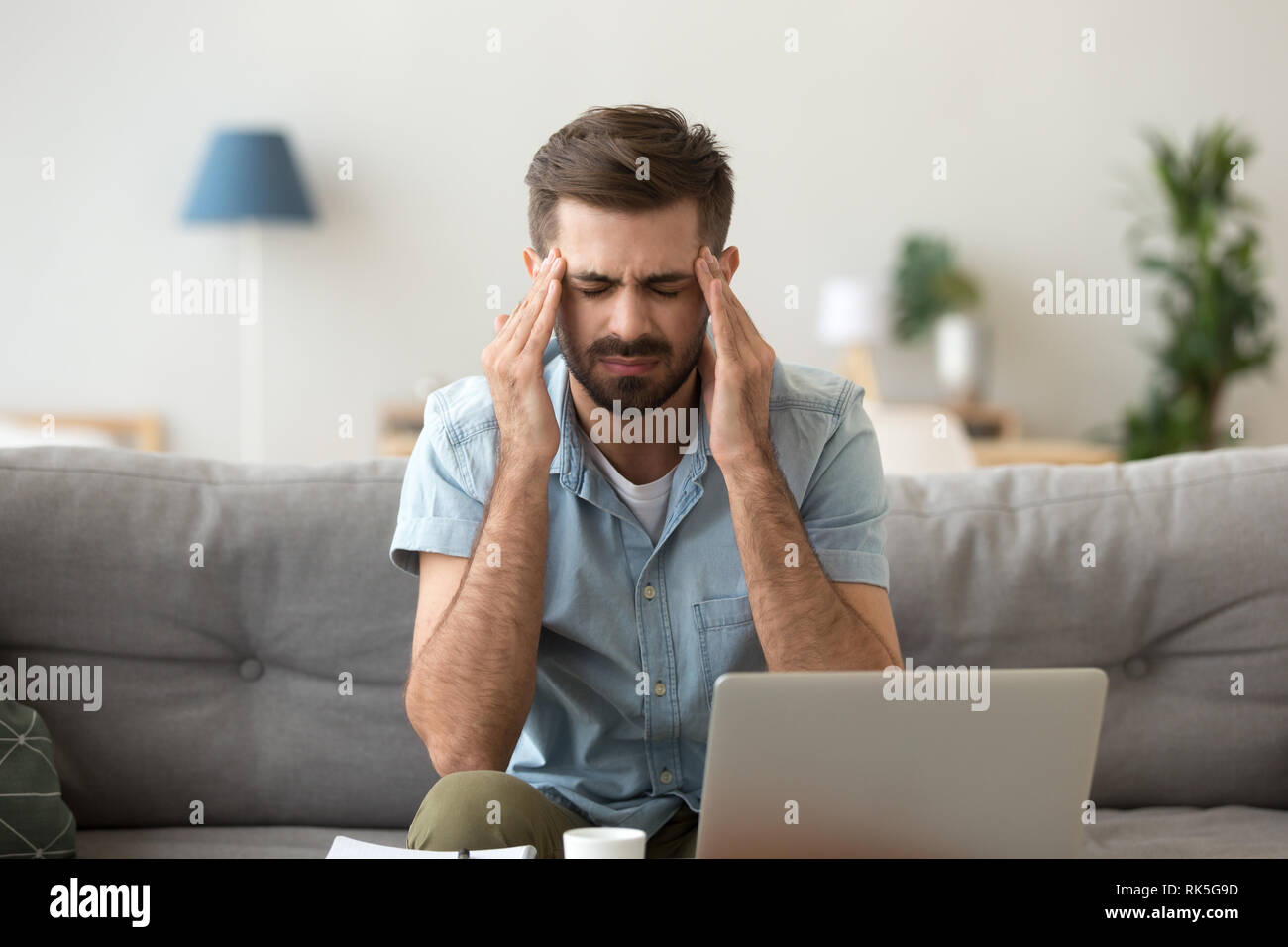 Tired stressed young man suffering from headache after computer work ...