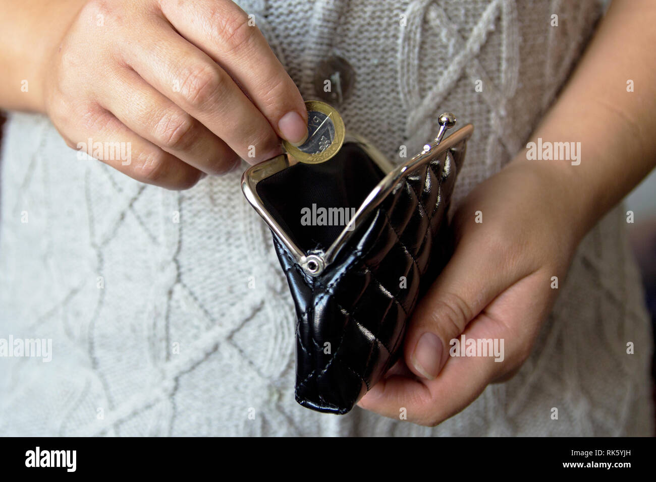 The woman holds the coins over the old empty wallet. The concept of ...