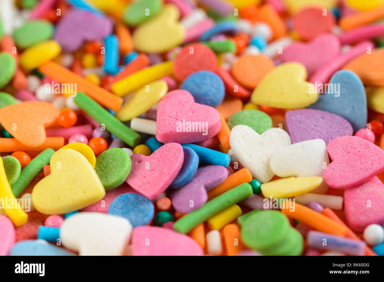Small sweets in heart shape scattered on orange background Stock Photo ...