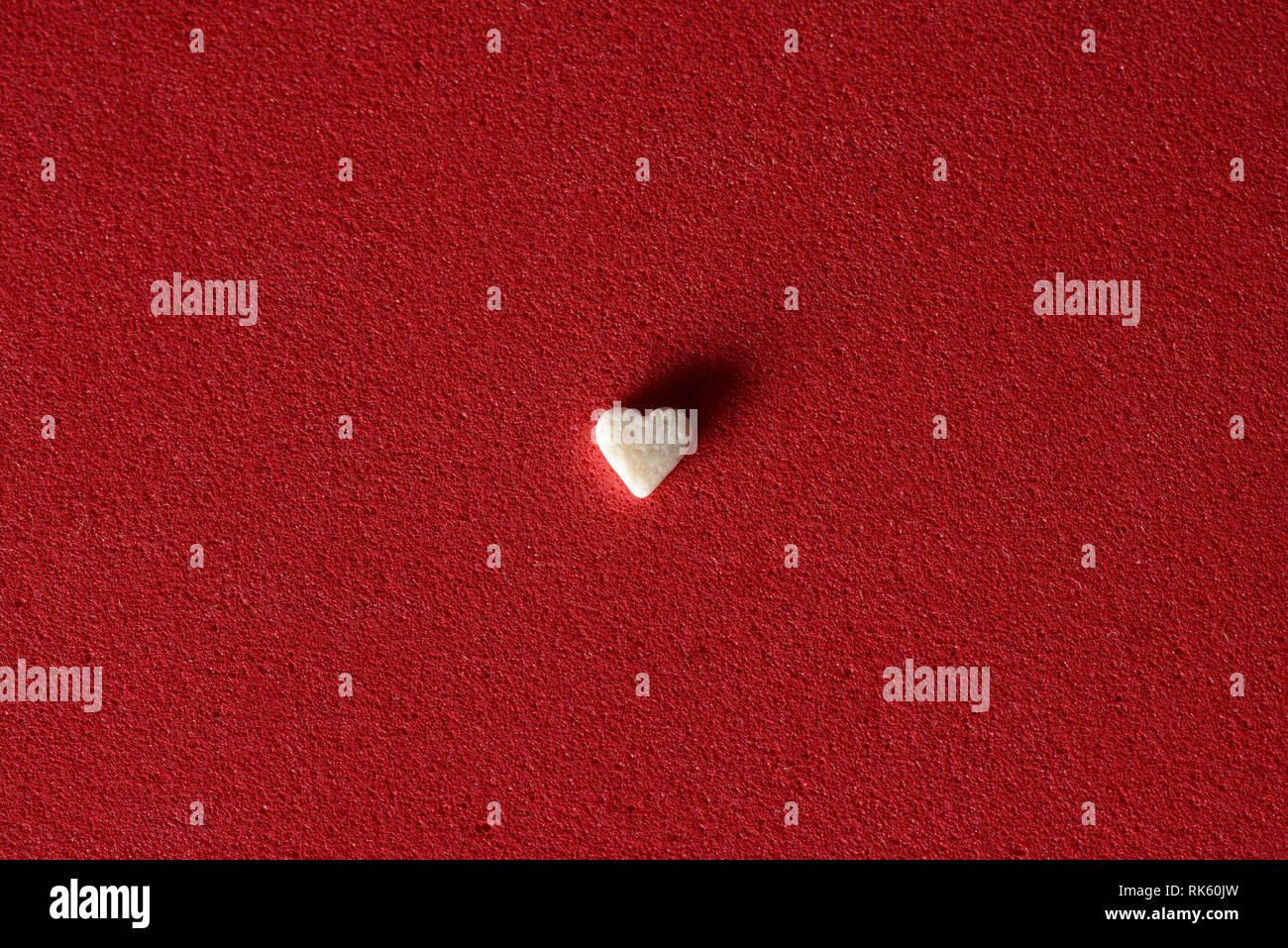 Small sugar heart shaped candy on red background Stock Photo - Alamy