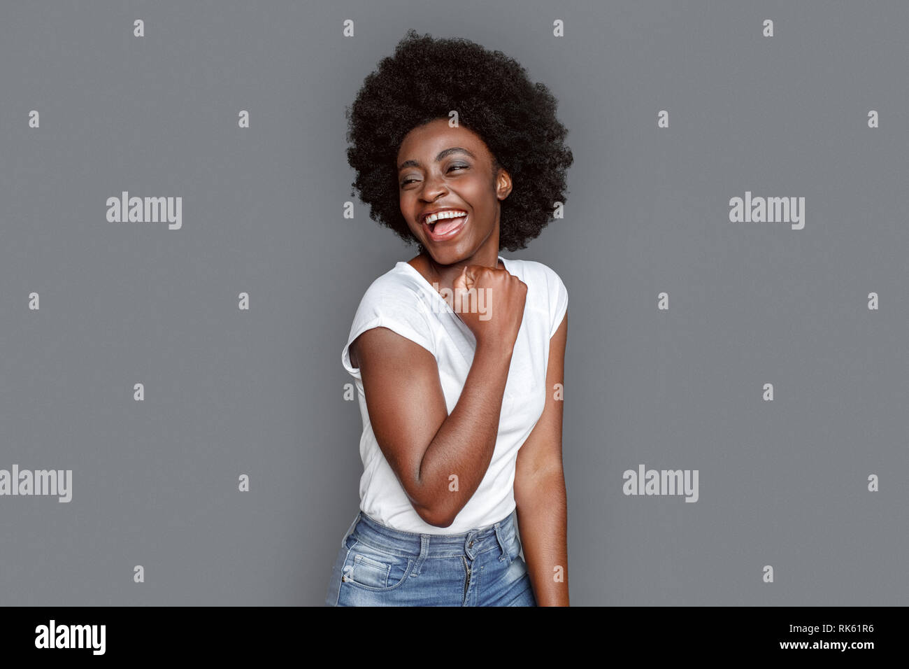 Young woman standing isolated on gray fist up victoriously laughing ...