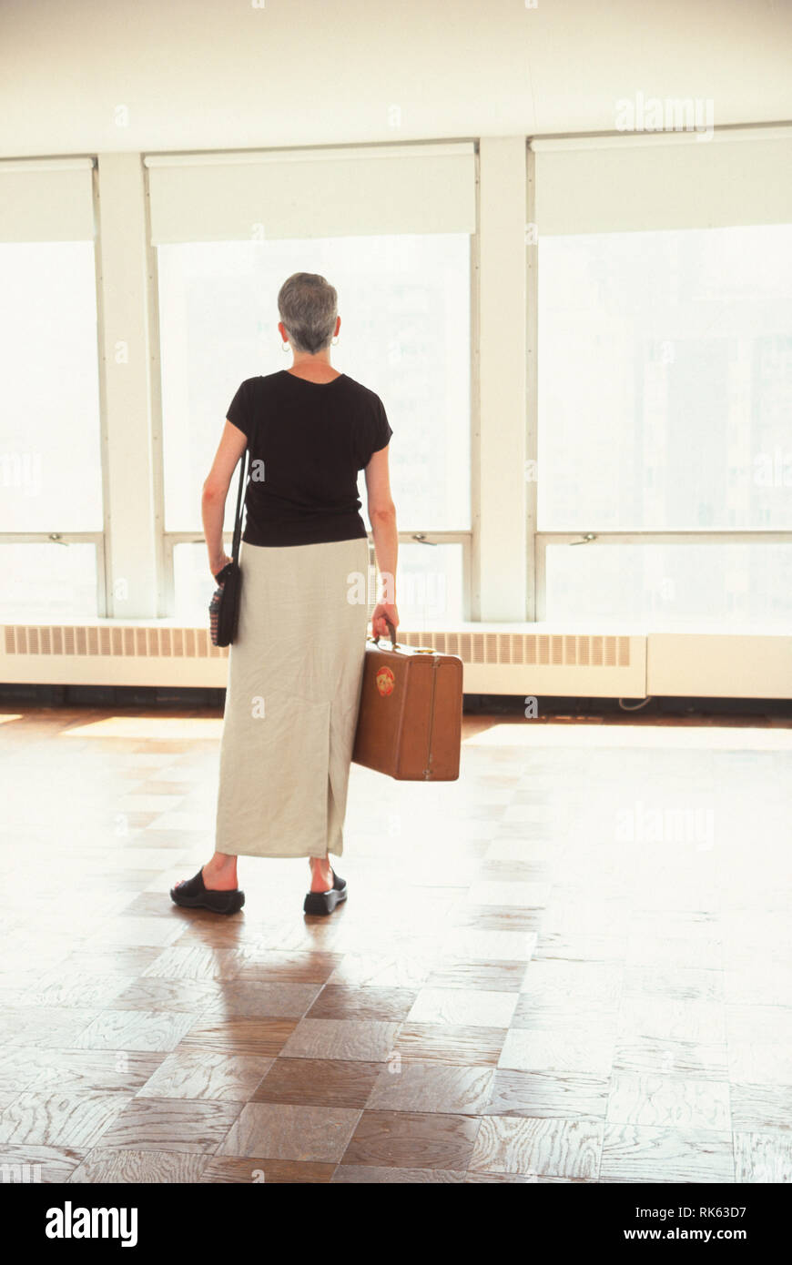 Mature woman contemplating arrival at her new apartment in New York ...