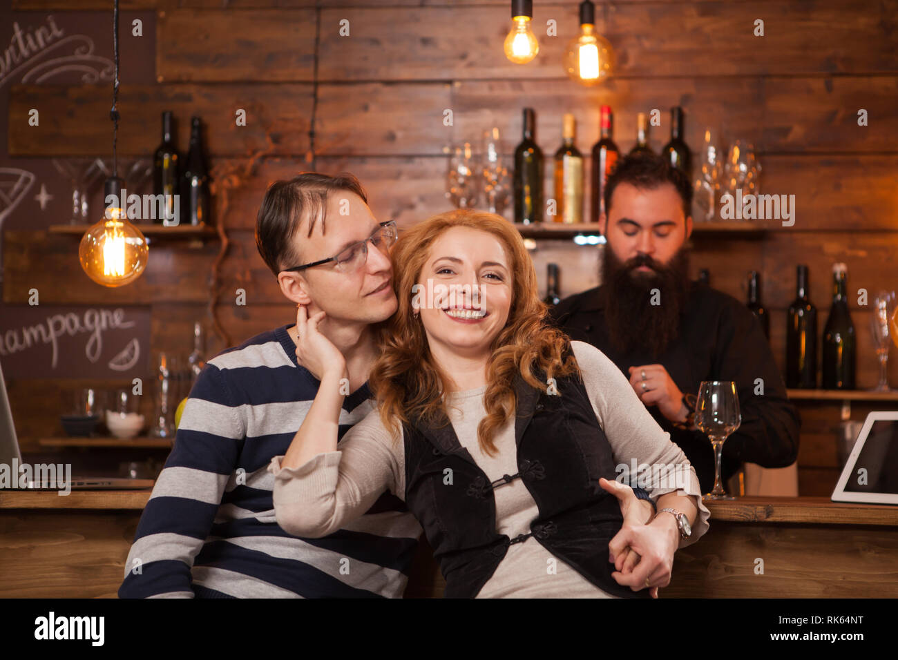 Young couple sitting at bar counter and showing affection. Having fun ...