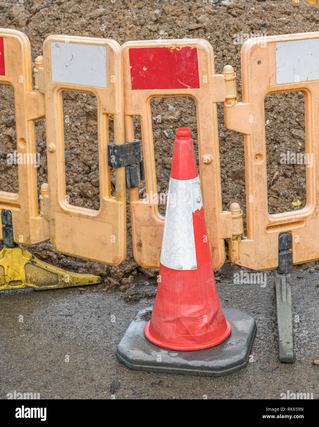 Orange traffic cone and safety barrier fencing at a roadworks site ...