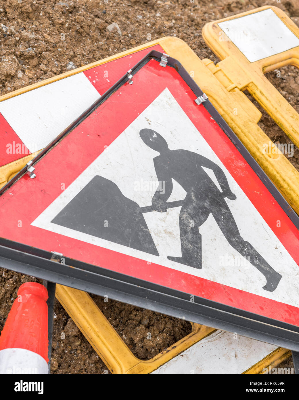 Roadworks sign, orange barrier fencing and traffic cone lying on the ...