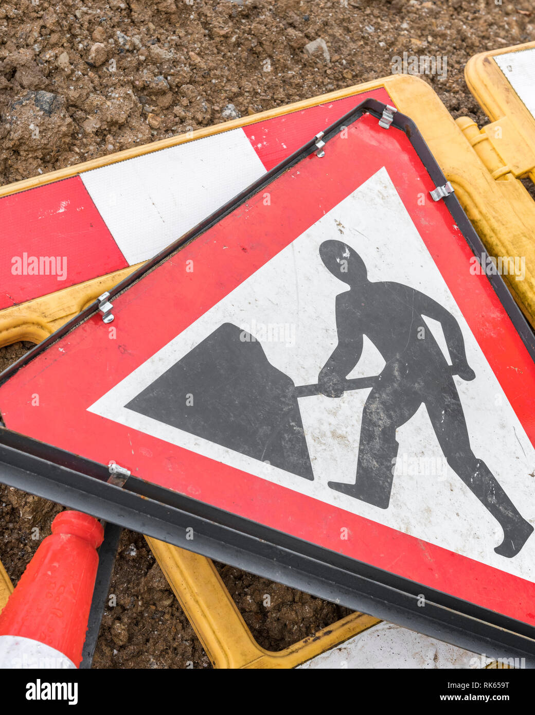 Roadworks sign, orange barrier fencing and traffic cone lying on the ...