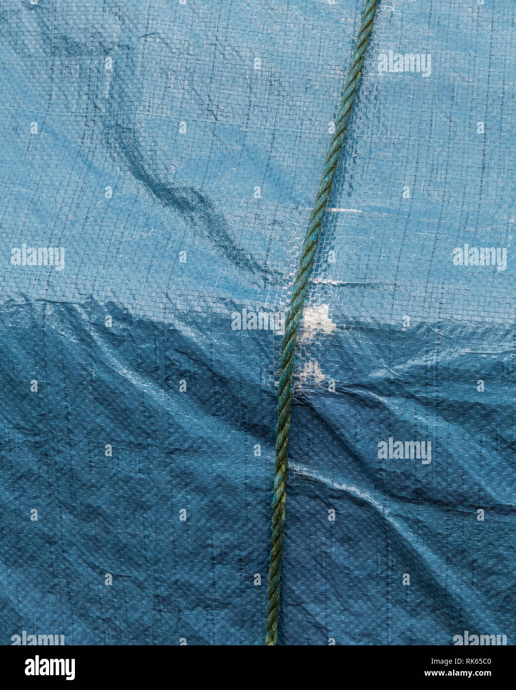 Polyester rope rubbing against blue plastic tarpaulin / plastic tarp ...