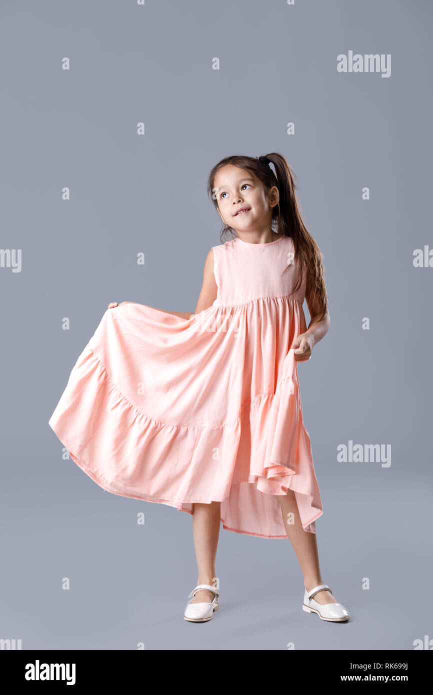 cute smiling little child girl in pink dress dancing on gray background ...