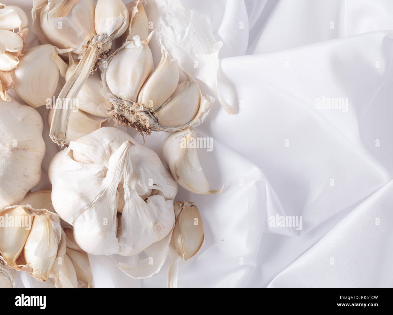 Bulbs and garlic cloves on white textile, top view Stock Photo - Alamy