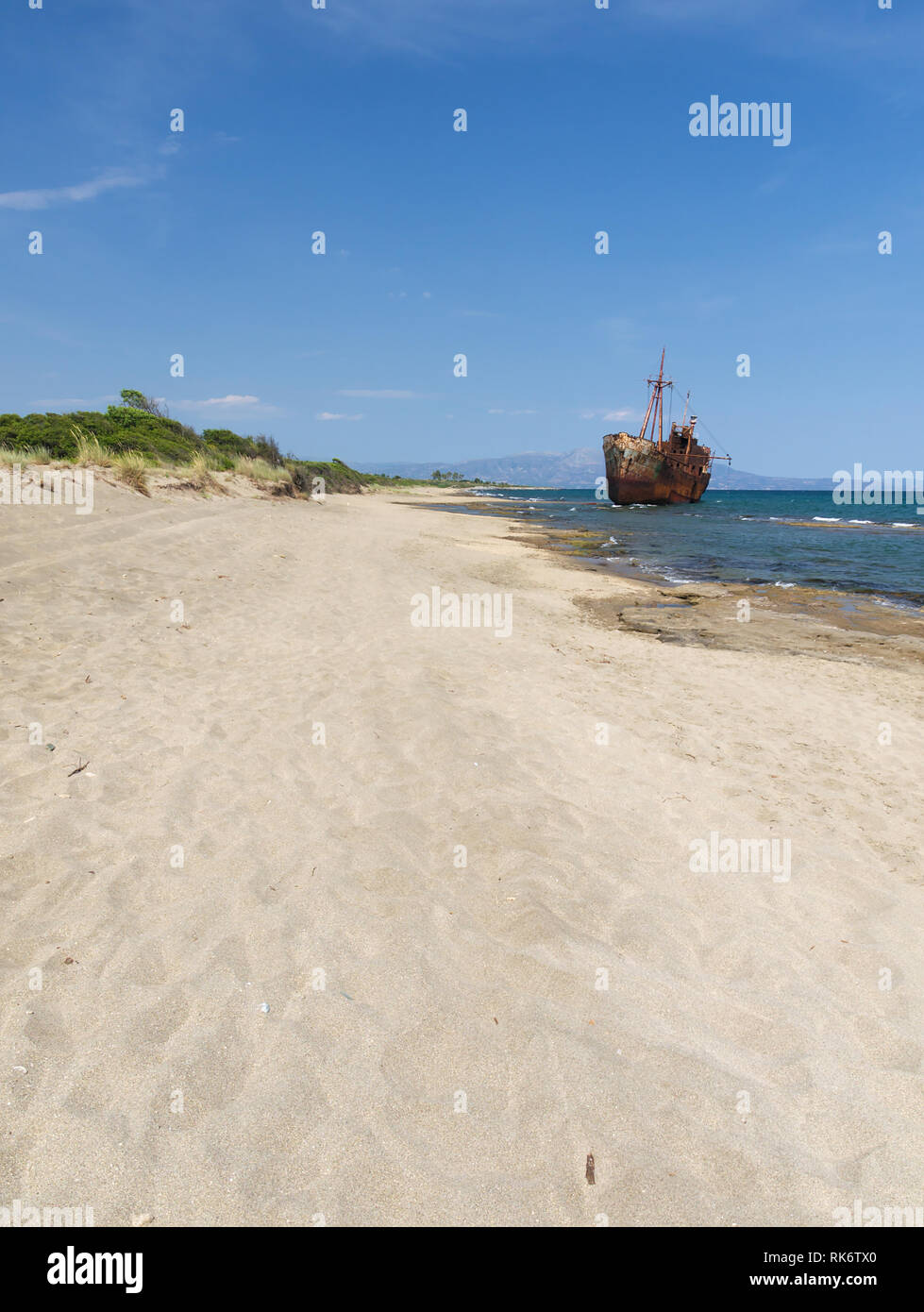 Rusty big ship shipwreck on Selinitsa beach under a deep blue sky at ...