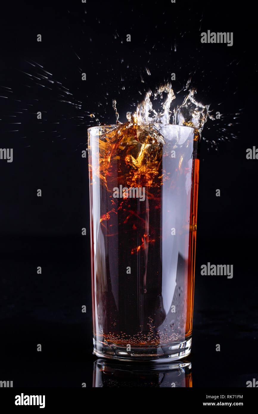 Dropping ice into a glass with a cold drink. Splash of drink in the bar ...