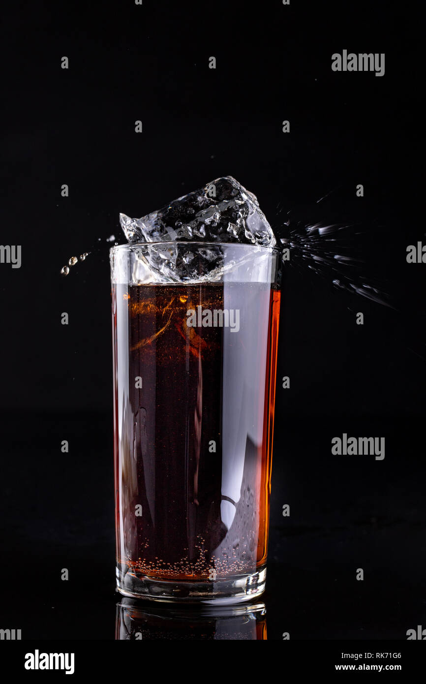 Dropping ice into a glass with a cold drink. Splash of drink in the bar ...