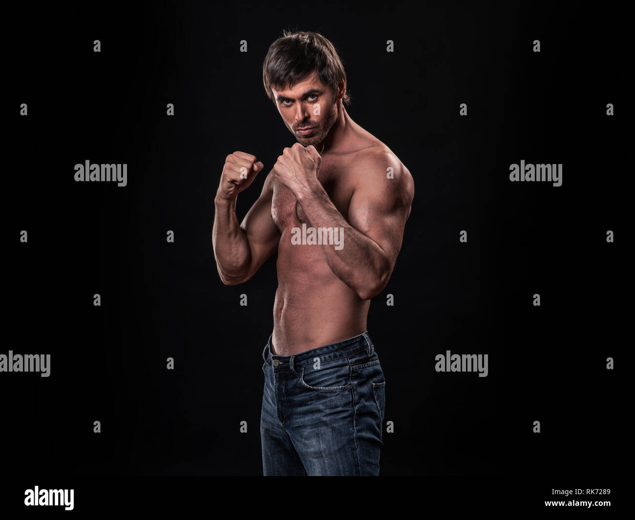 Muscular man in fighting stance holding fists ready to fight black ...