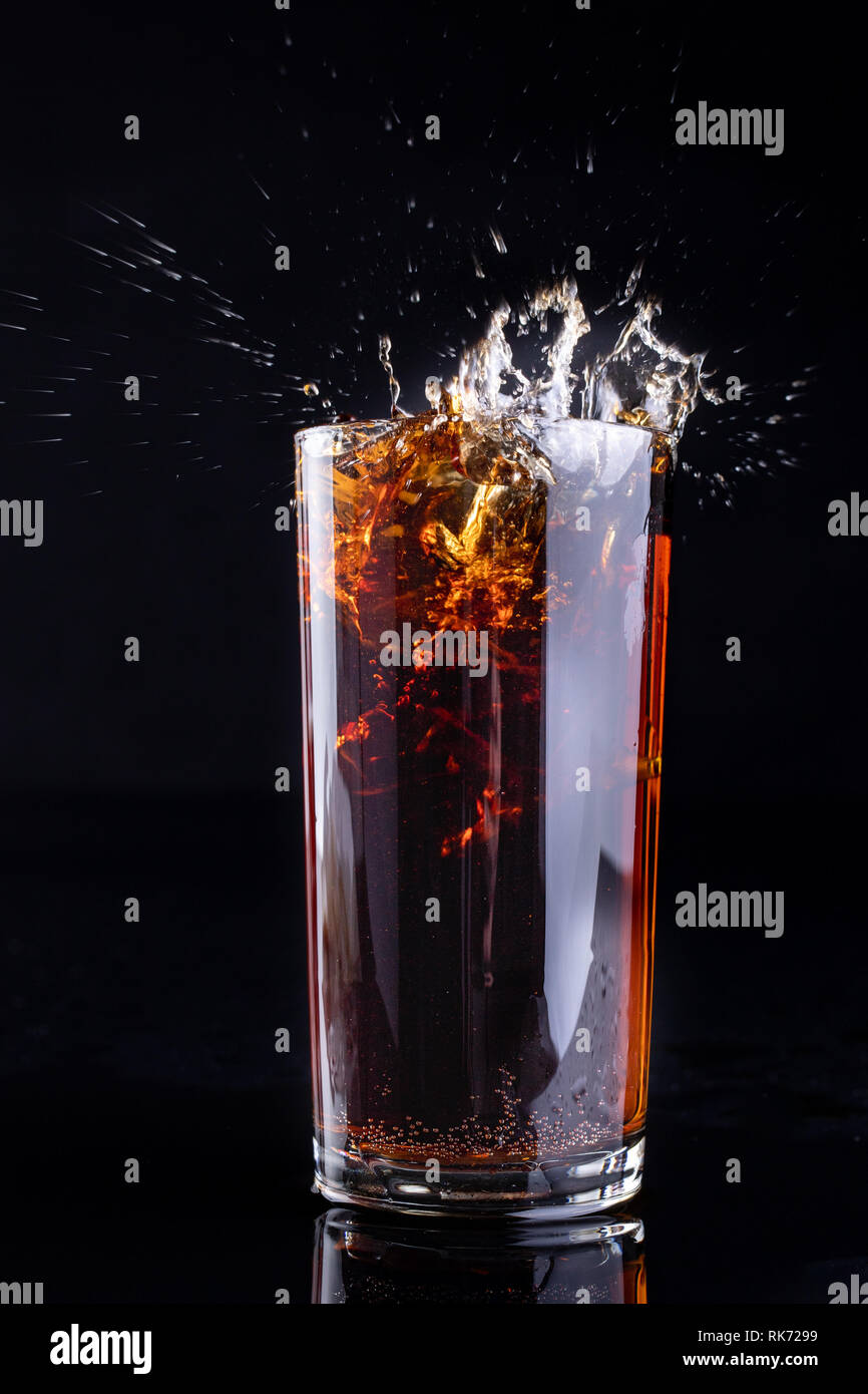 Dropping ice into a glass with a cold drink. Splash of drink in the bar ...