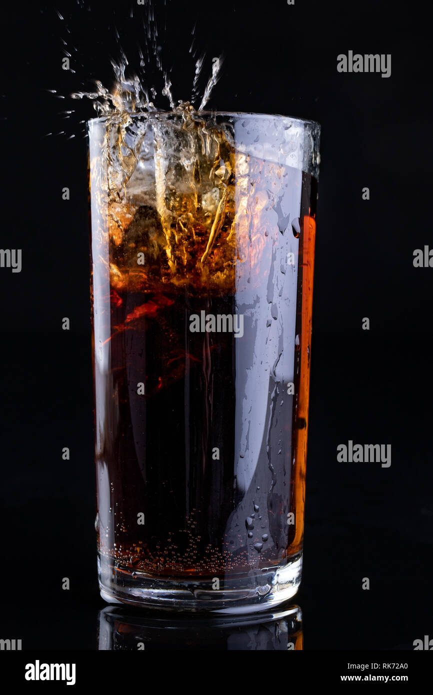 Dropping ice into a glass with a cold drink. Splash of drink in the bar ...