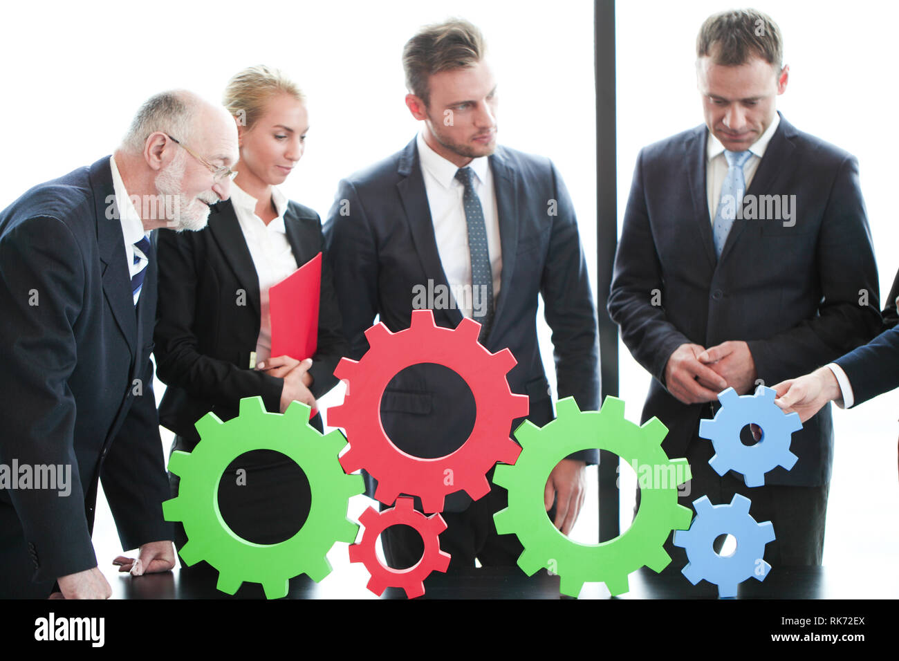 Business people assembling cogwheels, teamwork concept Stock Photo - Alamy