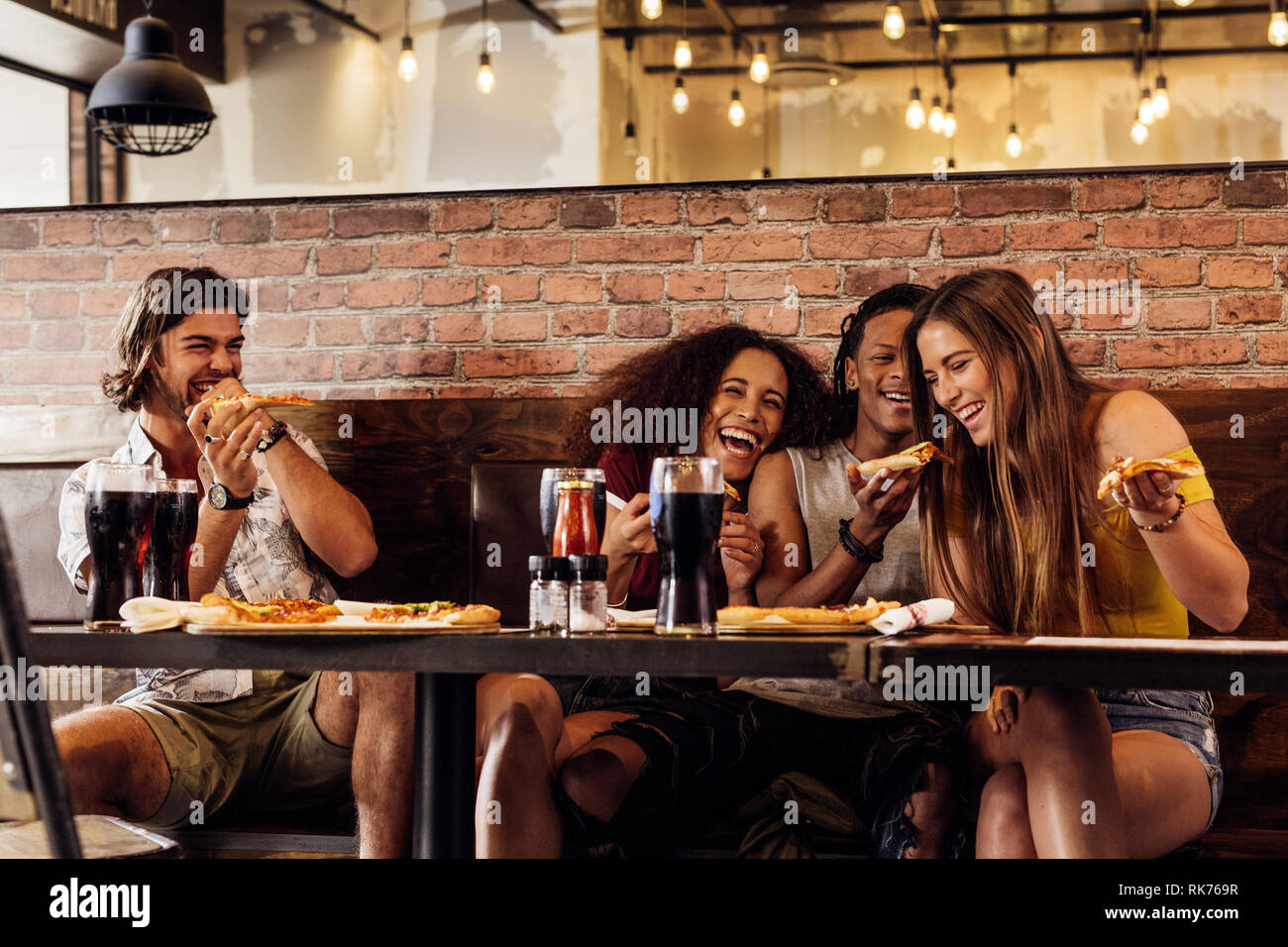 Group of friends having pizza at cafe. Cheerful young people eating ... Group of friends having pizza at cafe. Cheerful young people eating ...