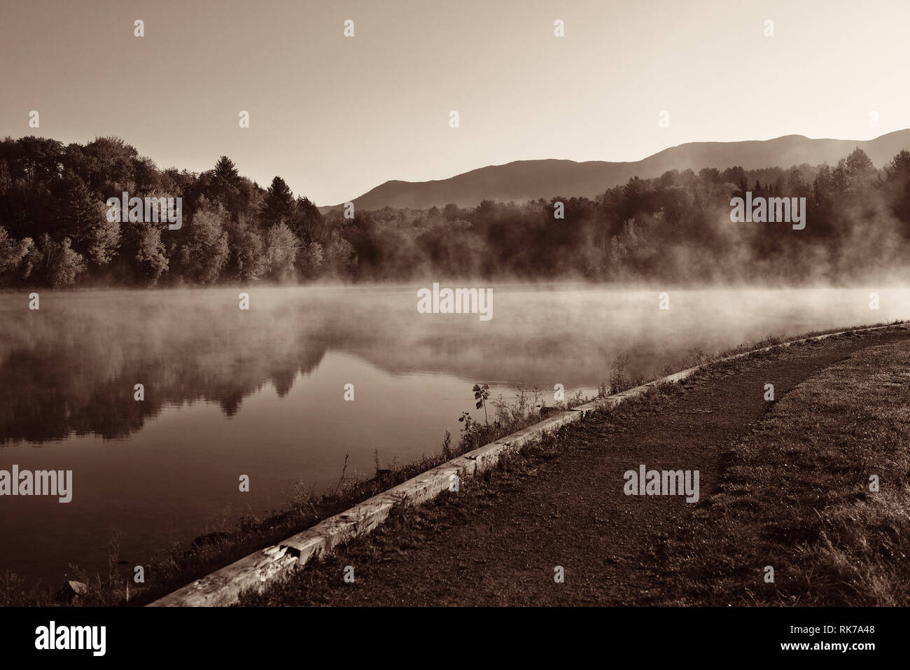 Lake fog in park with Autumn foliage and mountains with reflection in ...