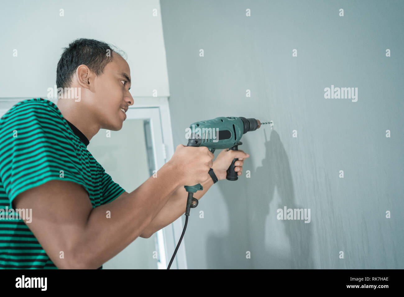 portrait of young man used a drill on the wall in the office room Stock ...