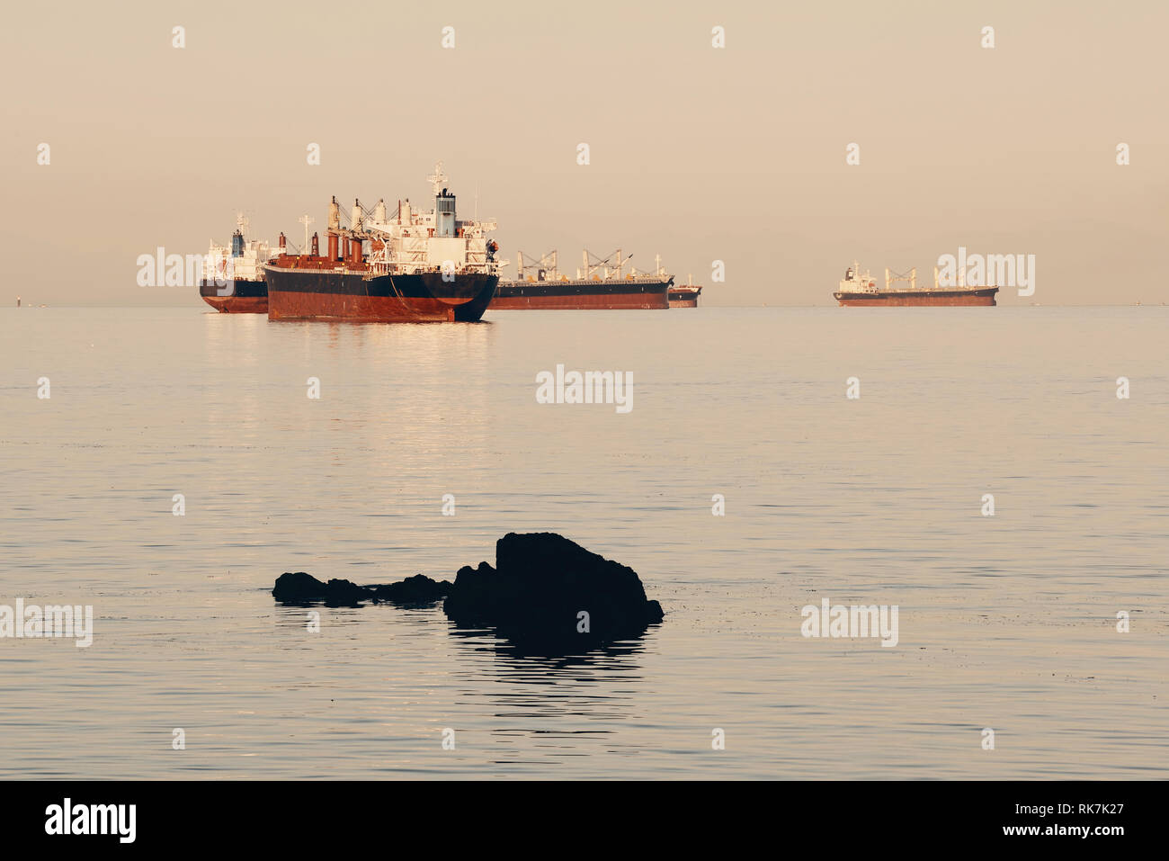 Cargo ship and rock in sea at sunrise in Vancouver Stock Photo - Alamy