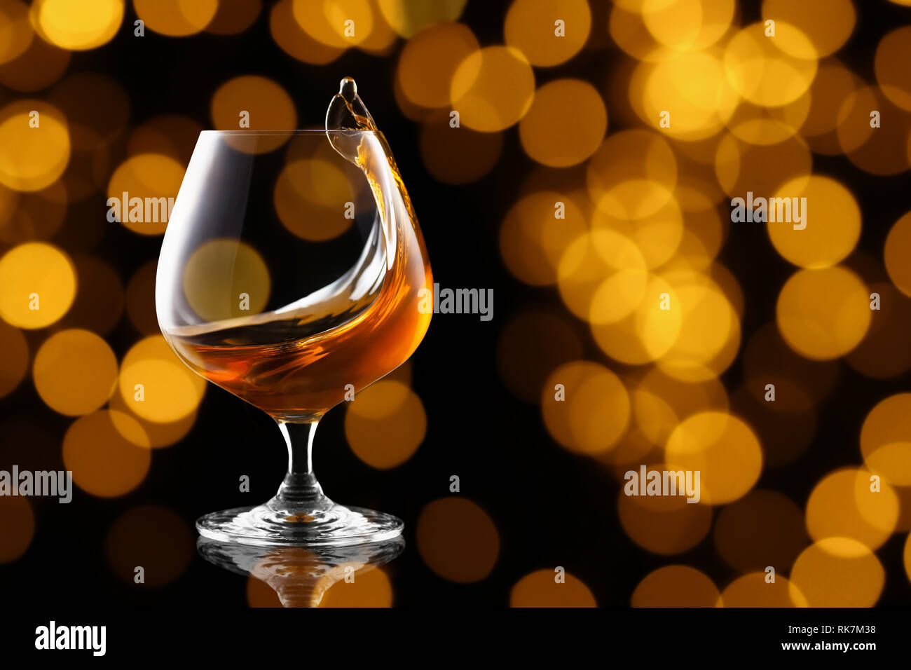 splash of brandy in snifter glass on blurry lights background Stock ...