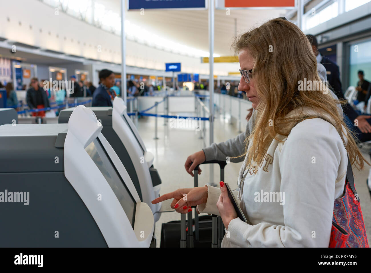 NEW YORK - MARCH 22, 2016: woman use check-in kiosk in JFK airport ...