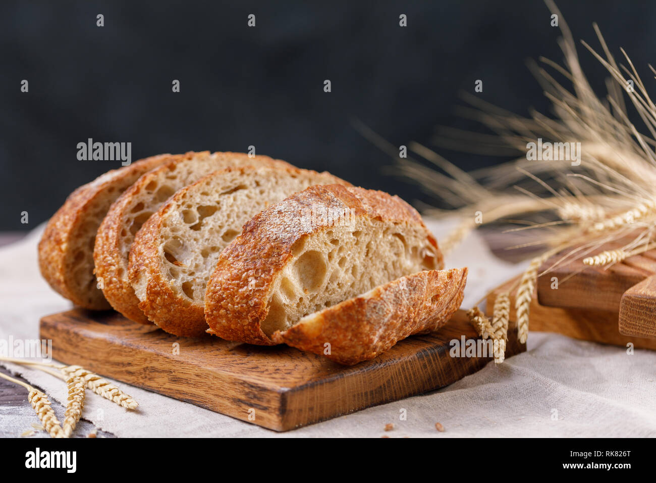 Sliced craft bread on a board close-up on a dark background. The ...