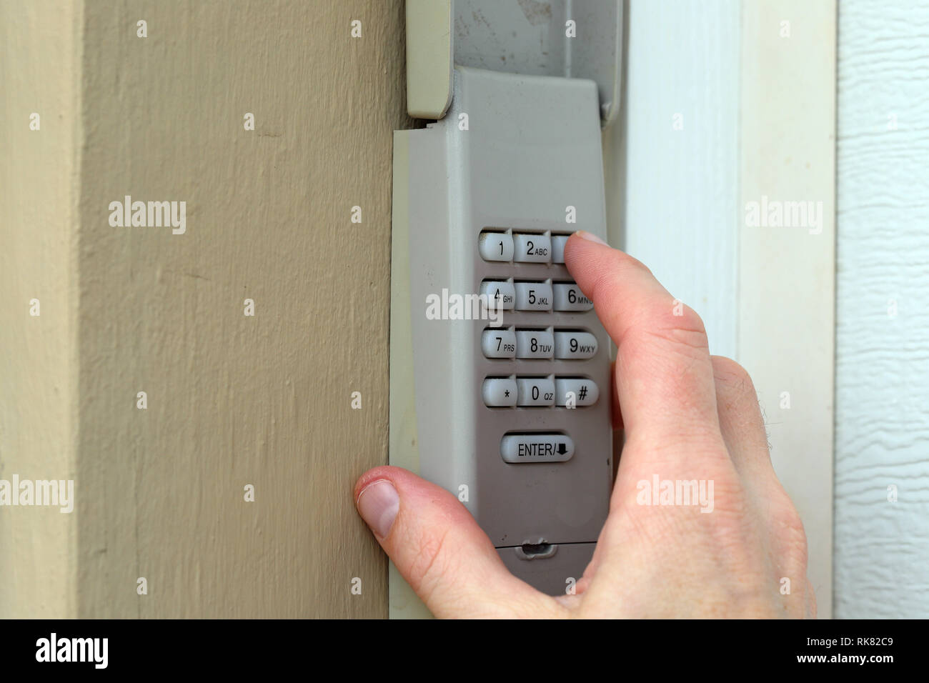 Hand enters code on keypad used on a garage door entrance to a home ...