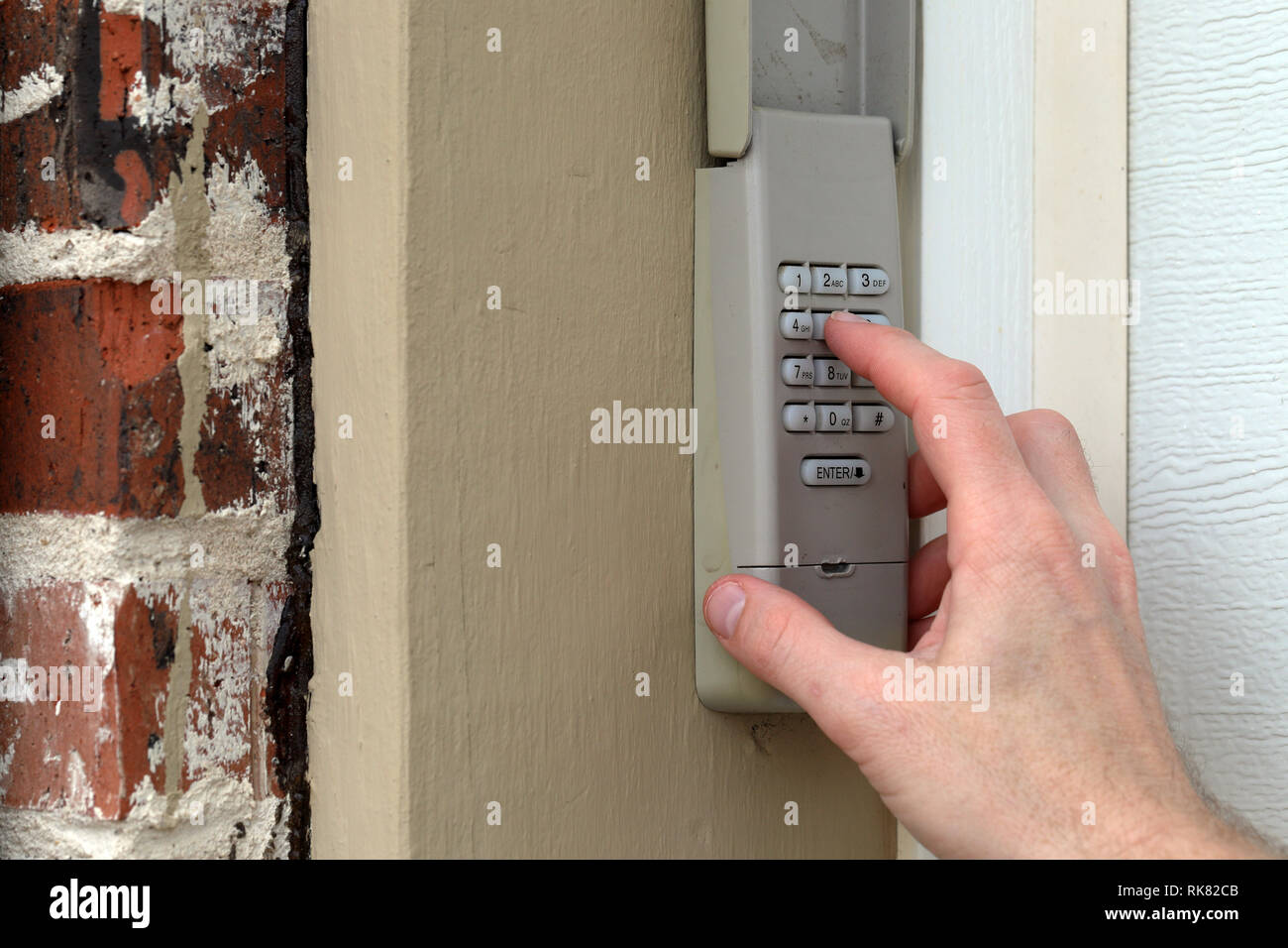 Hand enters code on keypad used on a garage door entrance to a home ...