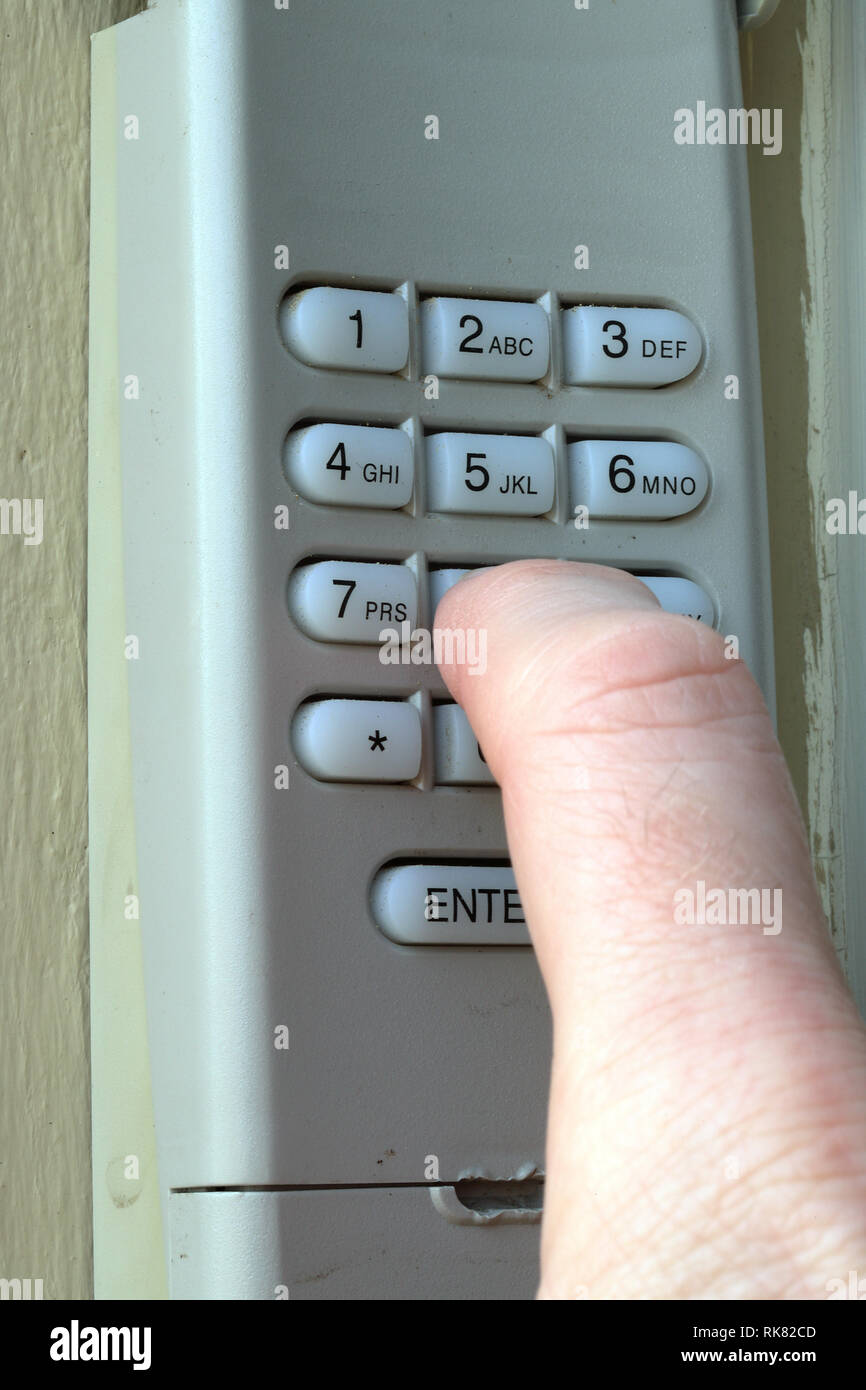 Hand enters code on keypad used on a garage door entrance to a home ...