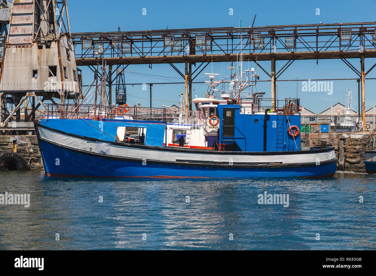 Small blue trawler boat standing by the pier Stock Photo - Alamy