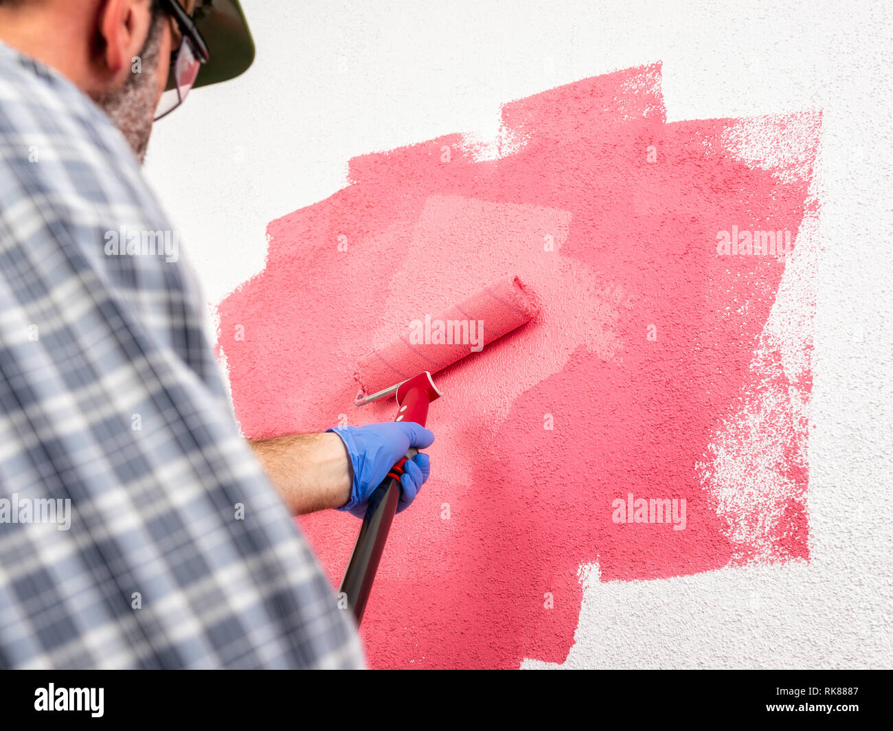 Caucasian house painter worker with helmet and goggles, with the roller ...
