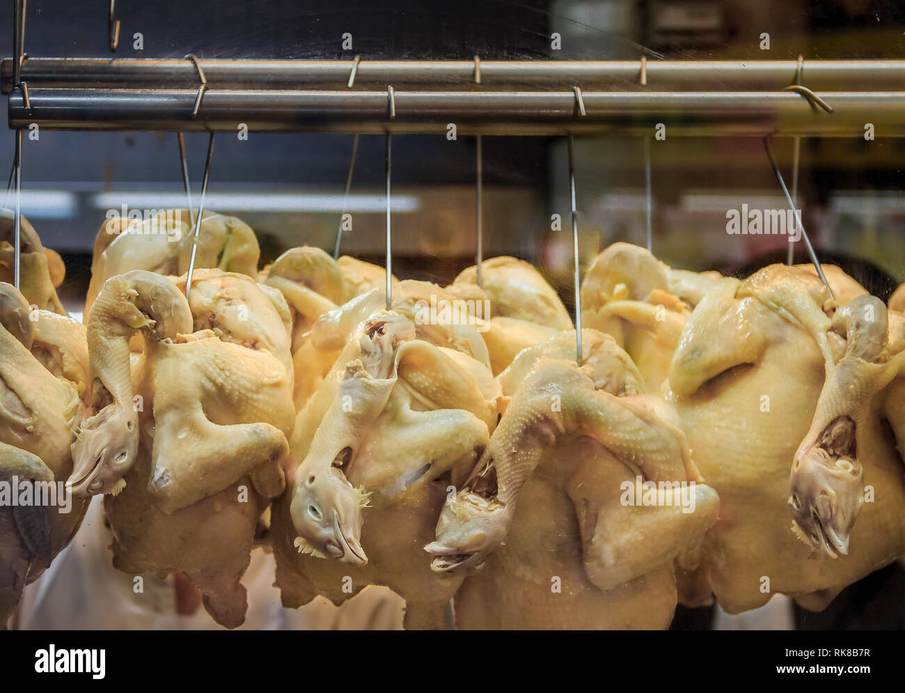 Whole poached chickens with heads hanging at a Hainanese Chicken Rice ...