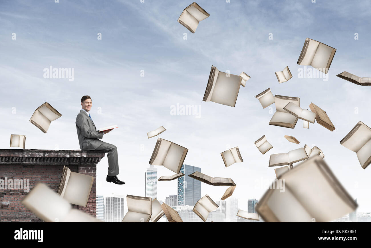 Man on roof reading book and many of them flying in air Stock Photo - Alamy