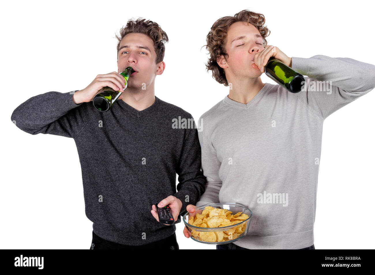 Two happy guys drinking beer and eating chips while watching football ...
