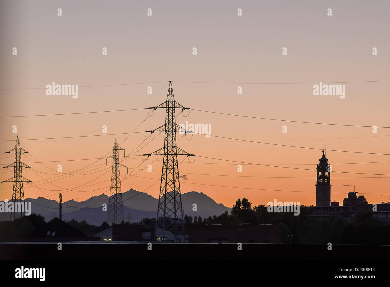 Silhouette of high voltage power line cables in an orange evening ...