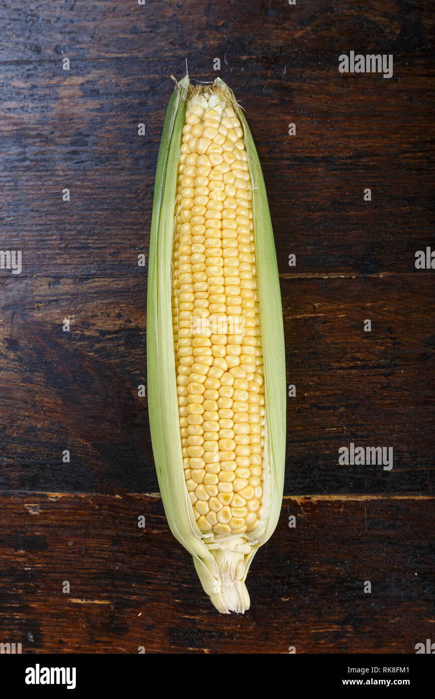 one head of raw sweet corn on a wooden background. space for text Stock ...