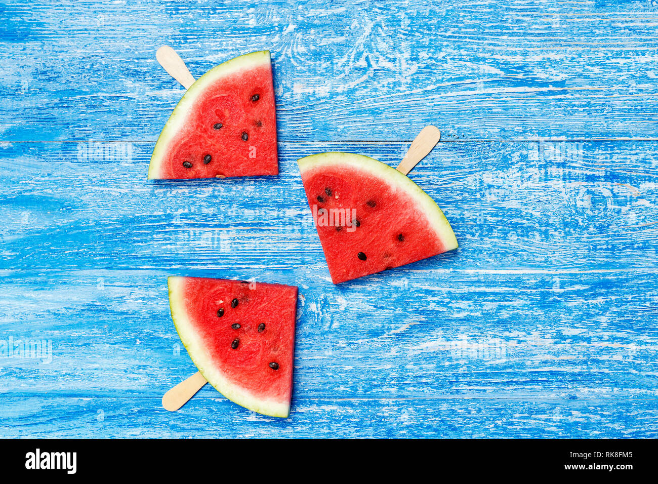 triangular slices of watermelon on a stick on a shabby blue background ...