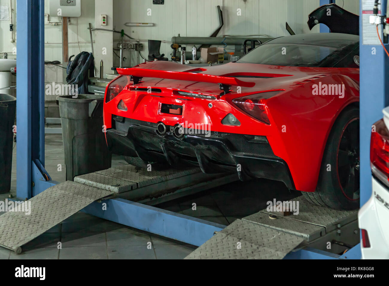 Red sports car raised on a lift in a car repair shop, rear bumper and ...