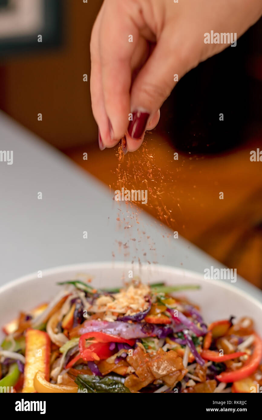 A hand sprinkling delicious spices over a Thai dish Stock Photo - Alamy