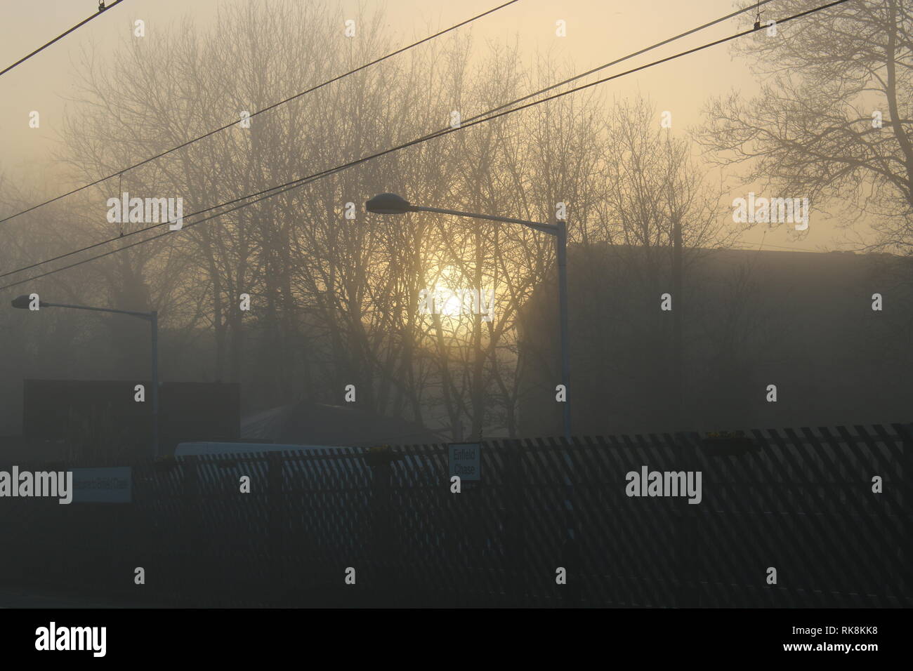Sunset through fog, trees and power lines at Enfield Chase train ...